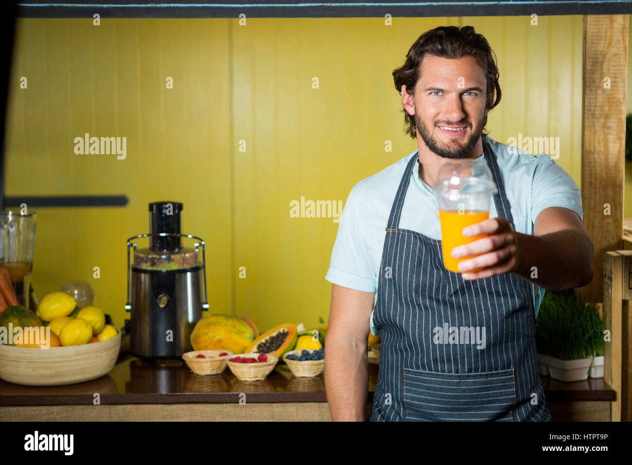 Smiling shop assistant offering the juice at the counter in health ...