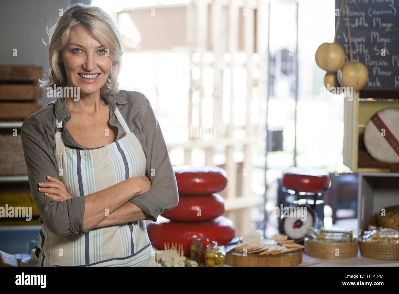 Portrait of female staff standing with arms crossed at counter in ...