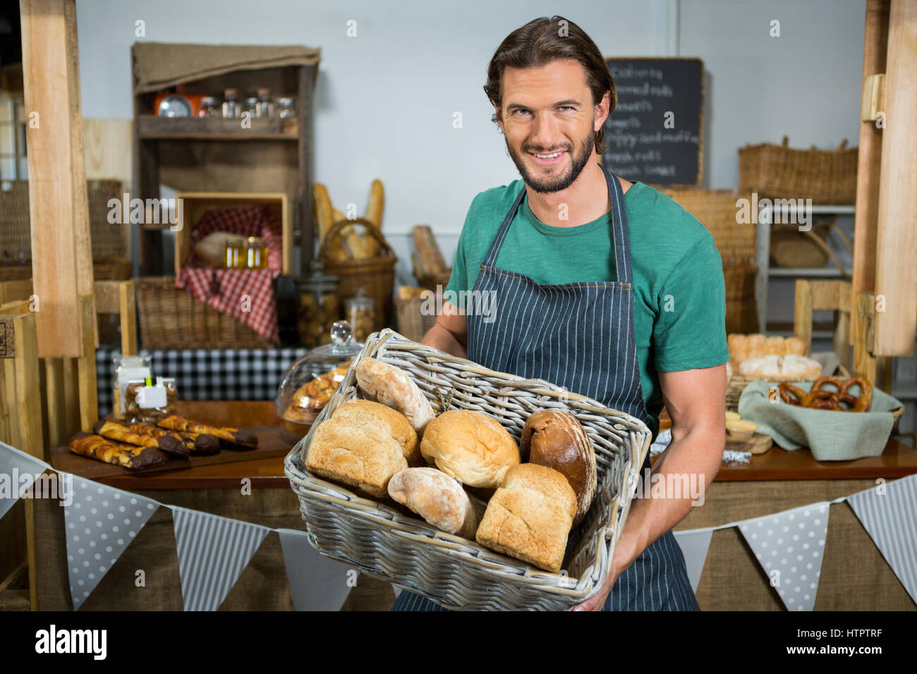 Portrait of male staff holding a basket of bread in bakery shop Stock ...