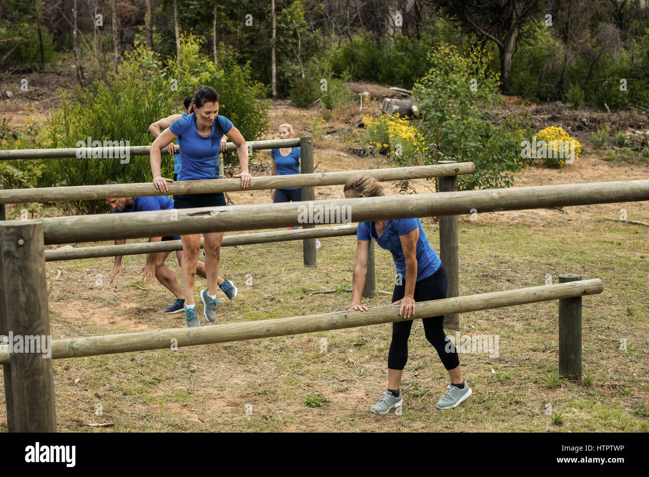 People jumping over the hurdles during obstacle course in boot camp ...