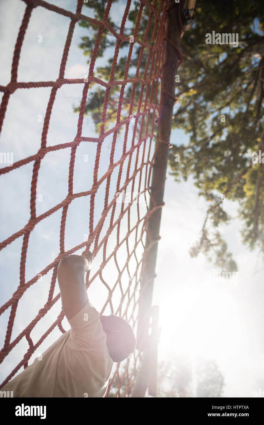 Military soldier climbing rope during obstacle course in boot camp ...