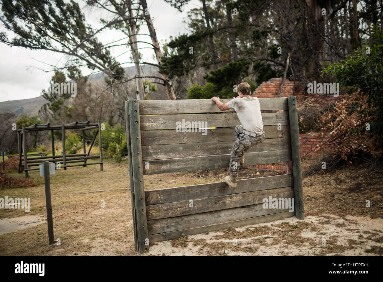 Rear view of soldier climbing wooden wall in boot camp Stock Photo - Alamy