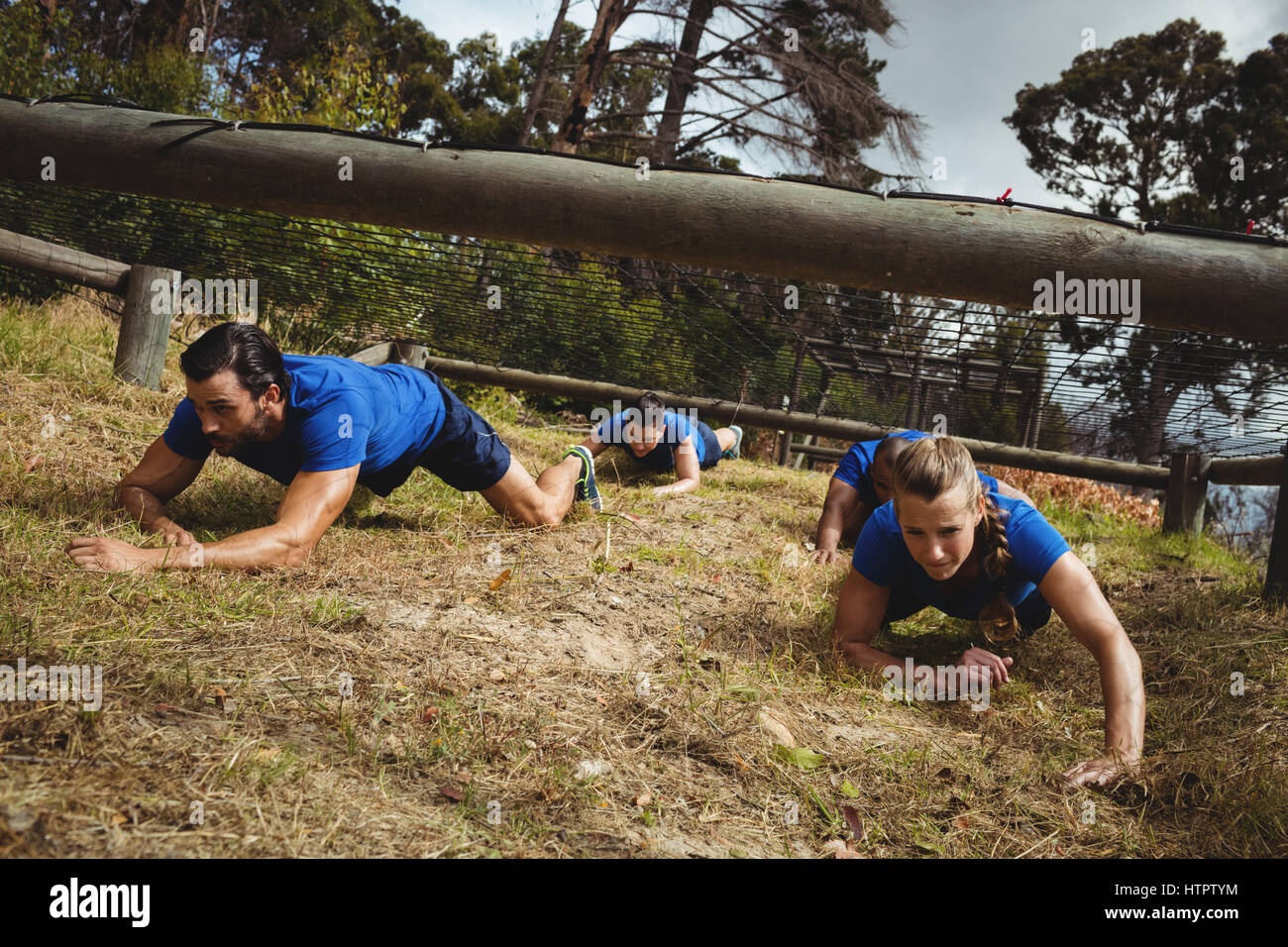 Fit people crawling under the net during obstacle course in bootcamp ...