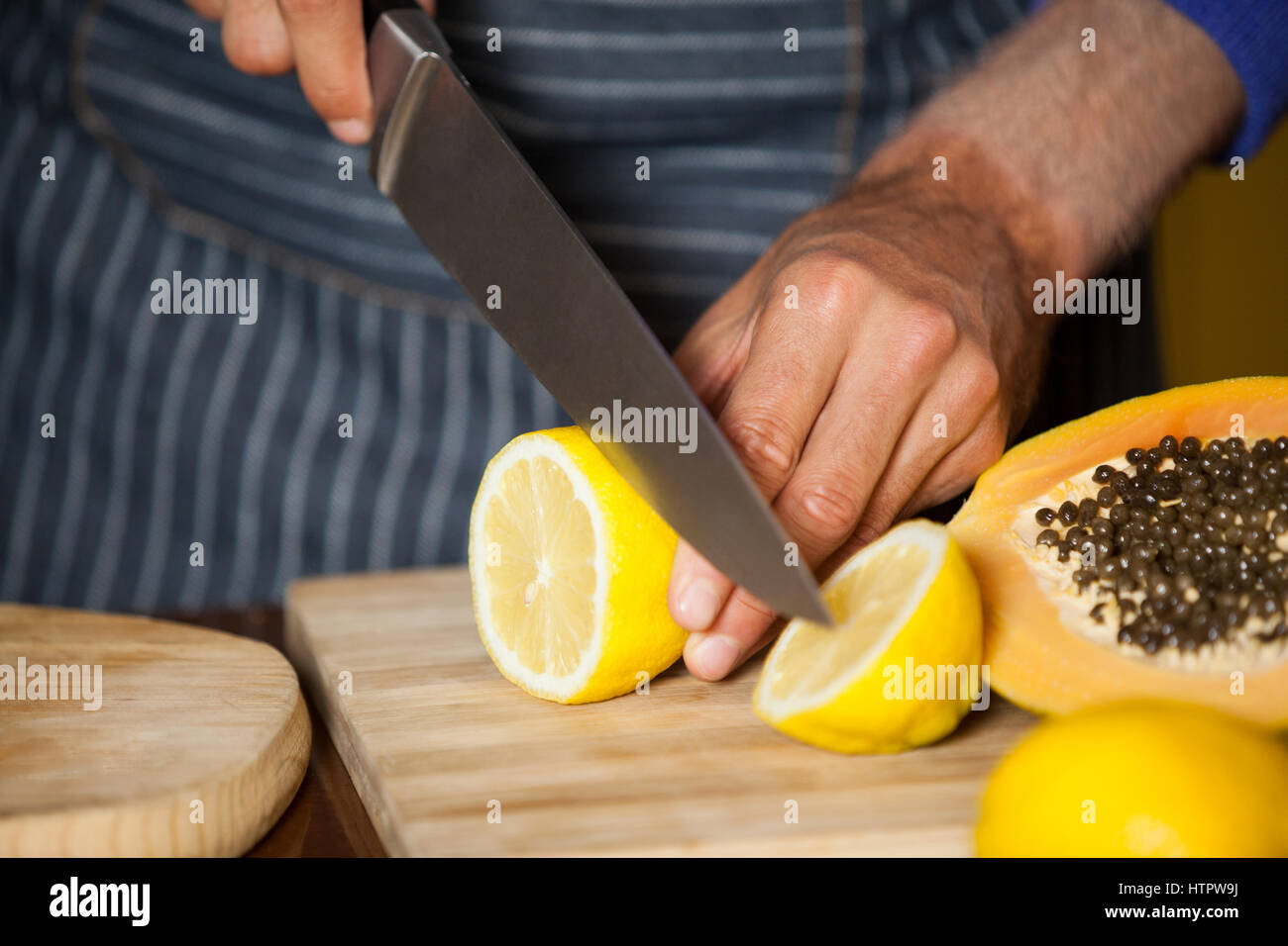 Mid-section of male staff cutting lemon in organic section of ...