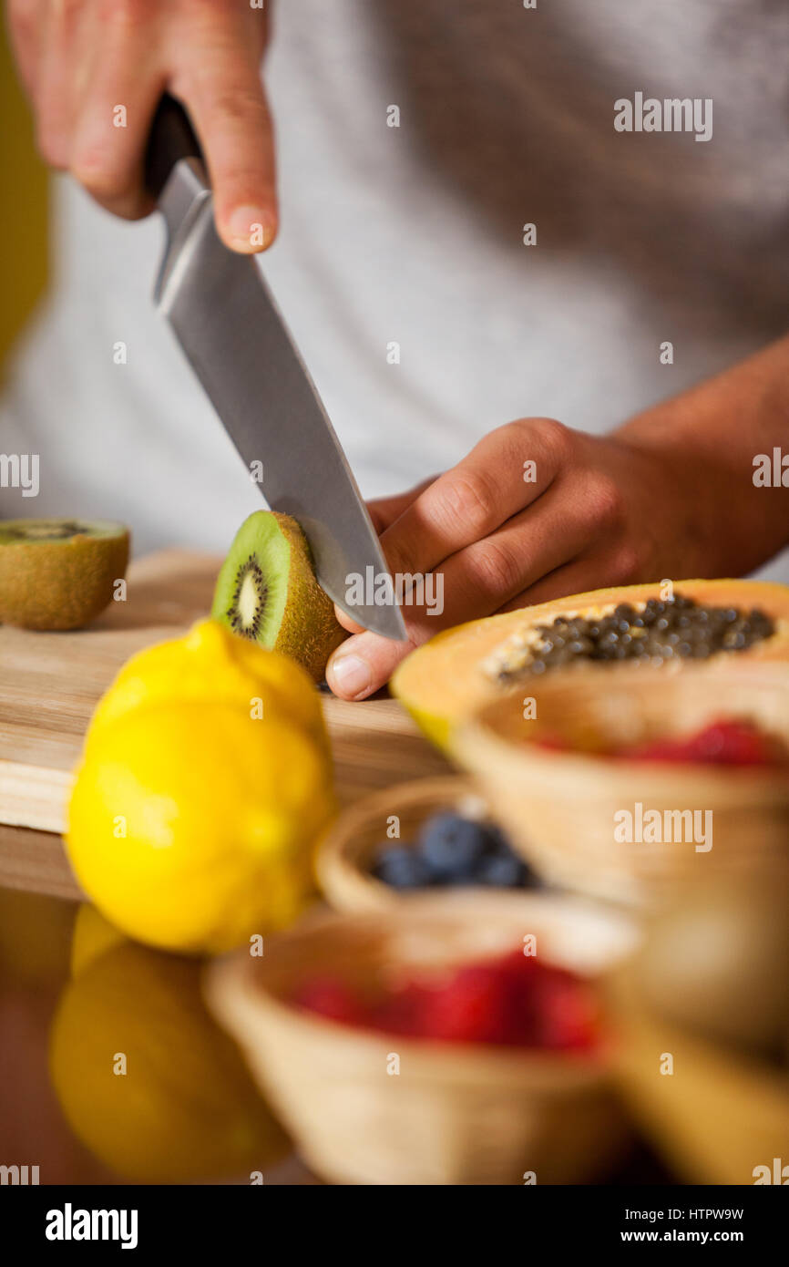 Mid-section of male staff cutting kiwifruit at organic section in ...
