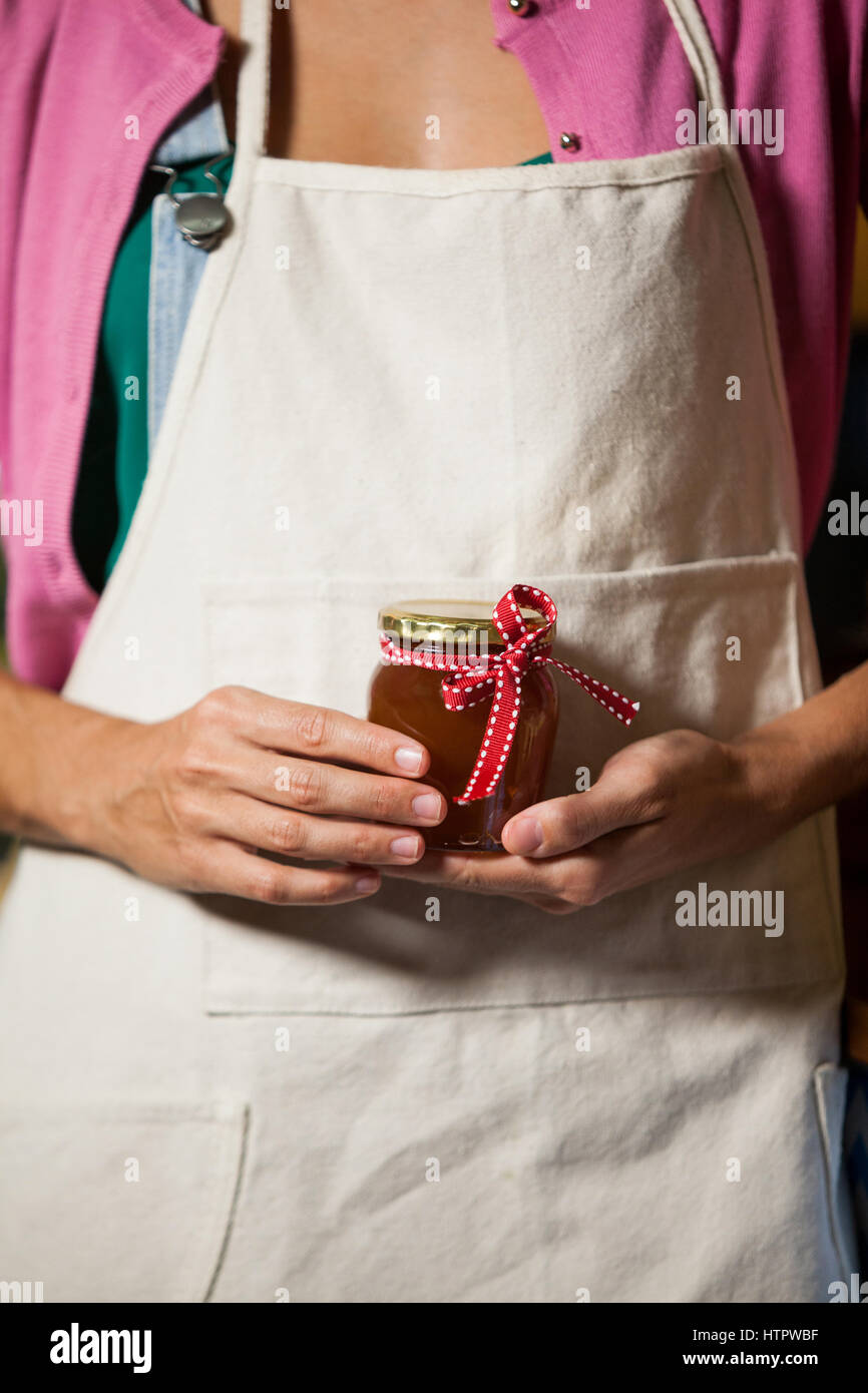 Mid-section of a female shop assistant holding a jar of jam Stock Photo ...