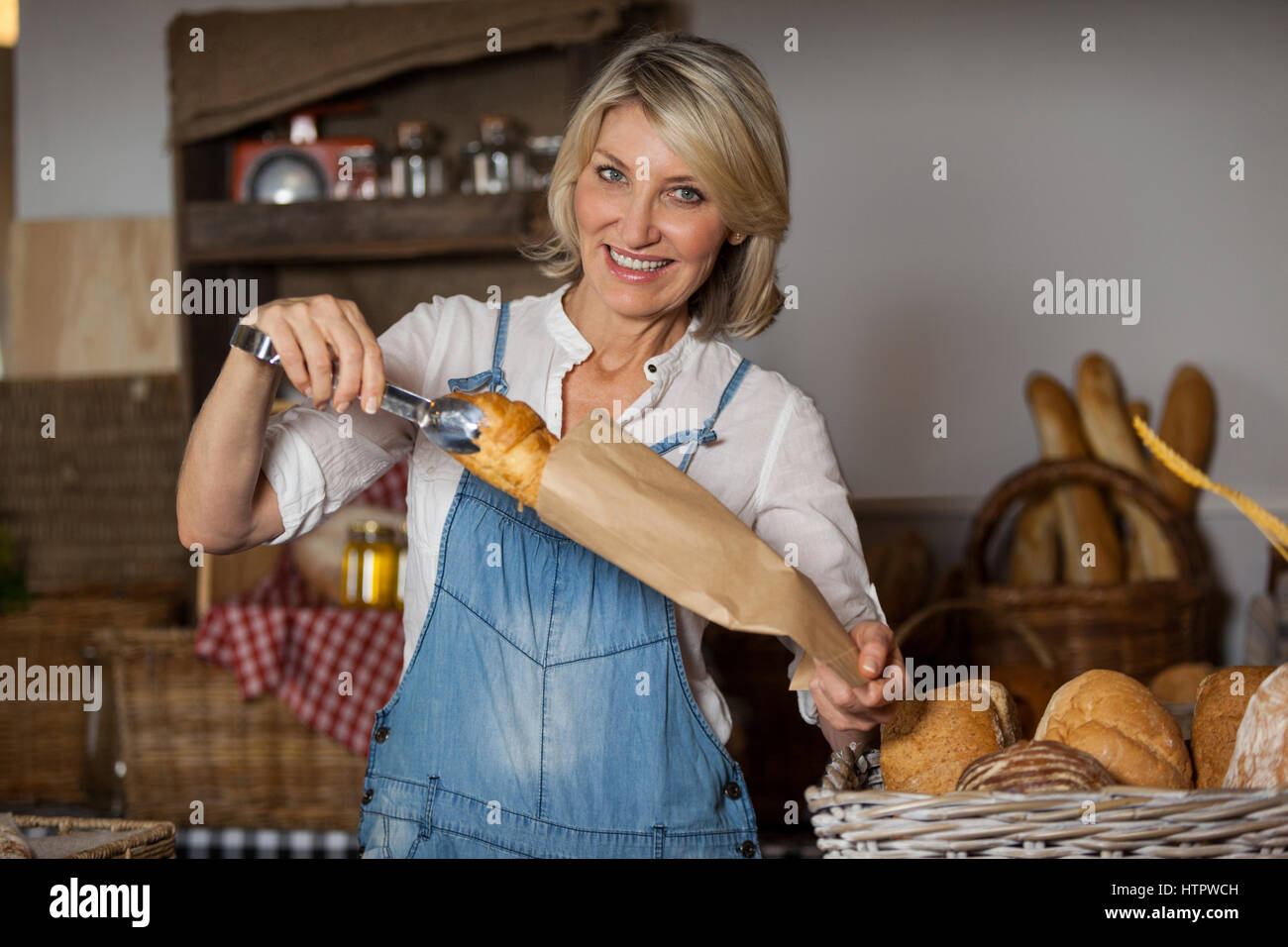 Female staff packing sweet food in paper bag at supermarket Stock Photo ...