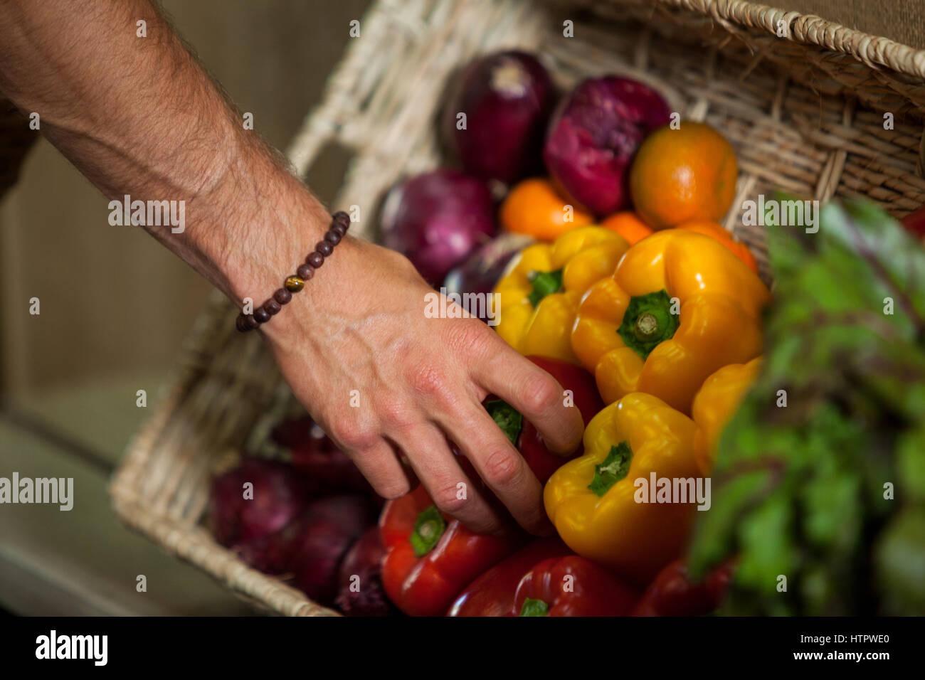 Hand of male staff selecting bell pepper in organic section of ...