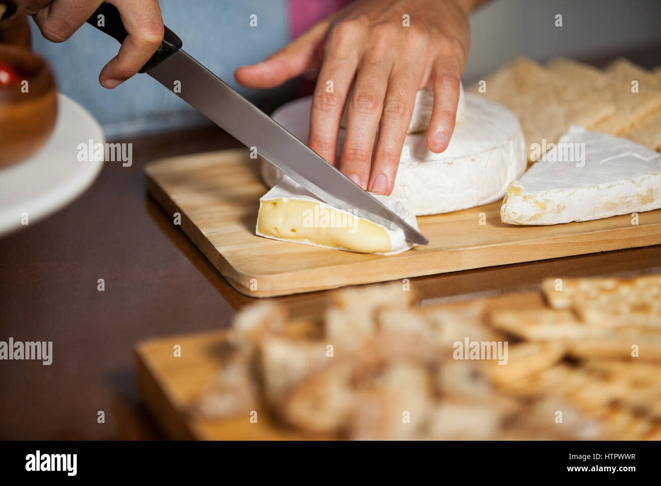 Hand of female staff cutting cheese at counter in market Stock Photo ...