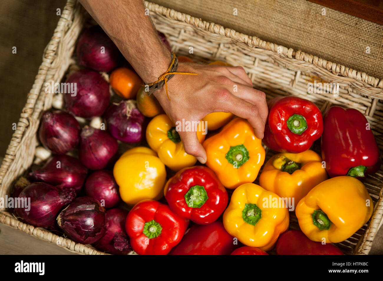 Hand of male staff selecting bell pepper in organic section of ...