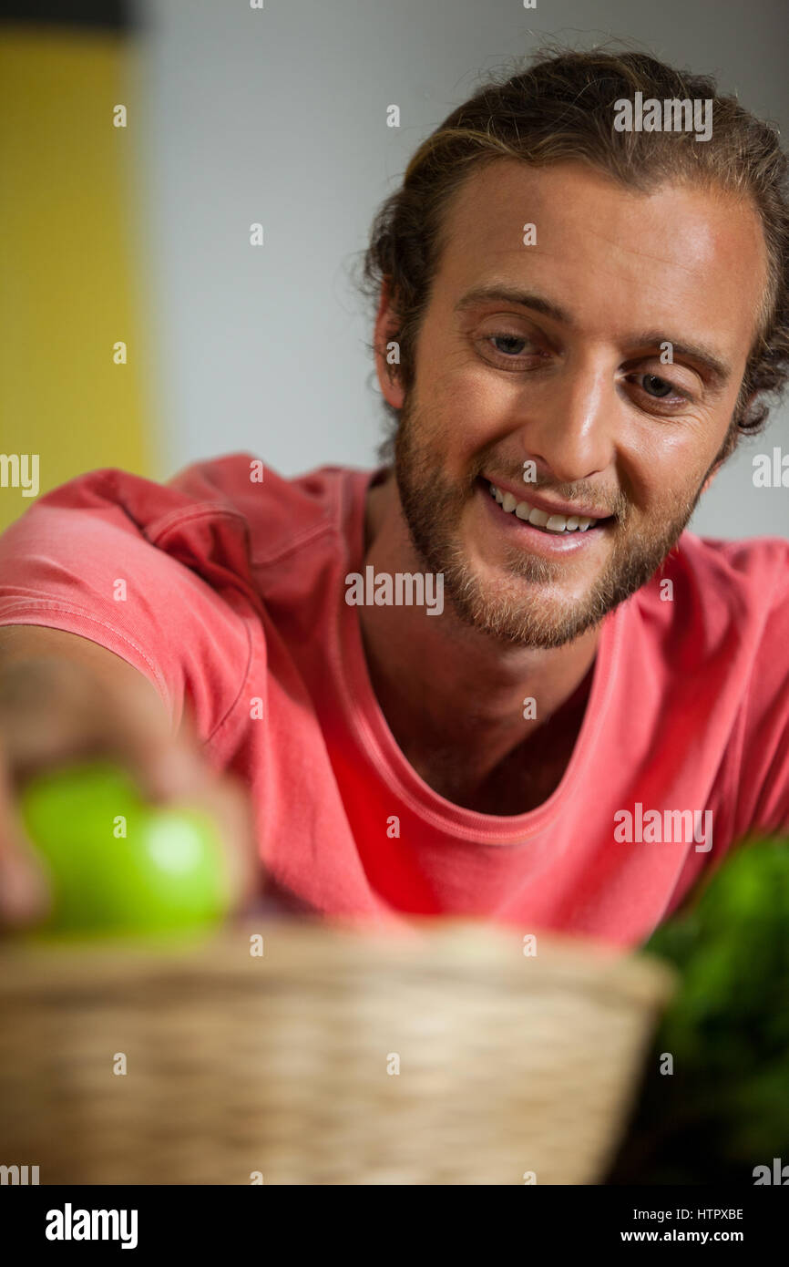 Smiling male staff arranging fruit in organic section of supermarket ...