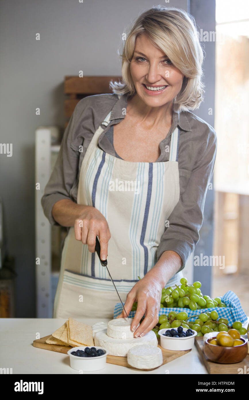 Portrait of female staff slicing cheese at counter of supermarket Stock ...