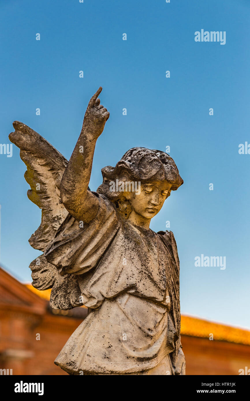 statue of young angel looking down and raising finger up to the sky ...