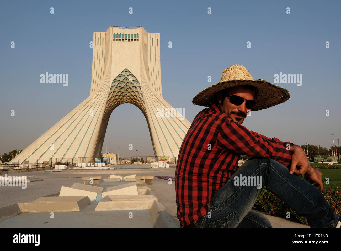 A tourist sits in front of the Azadi Tower or Freedom Tower in Azadi ...
