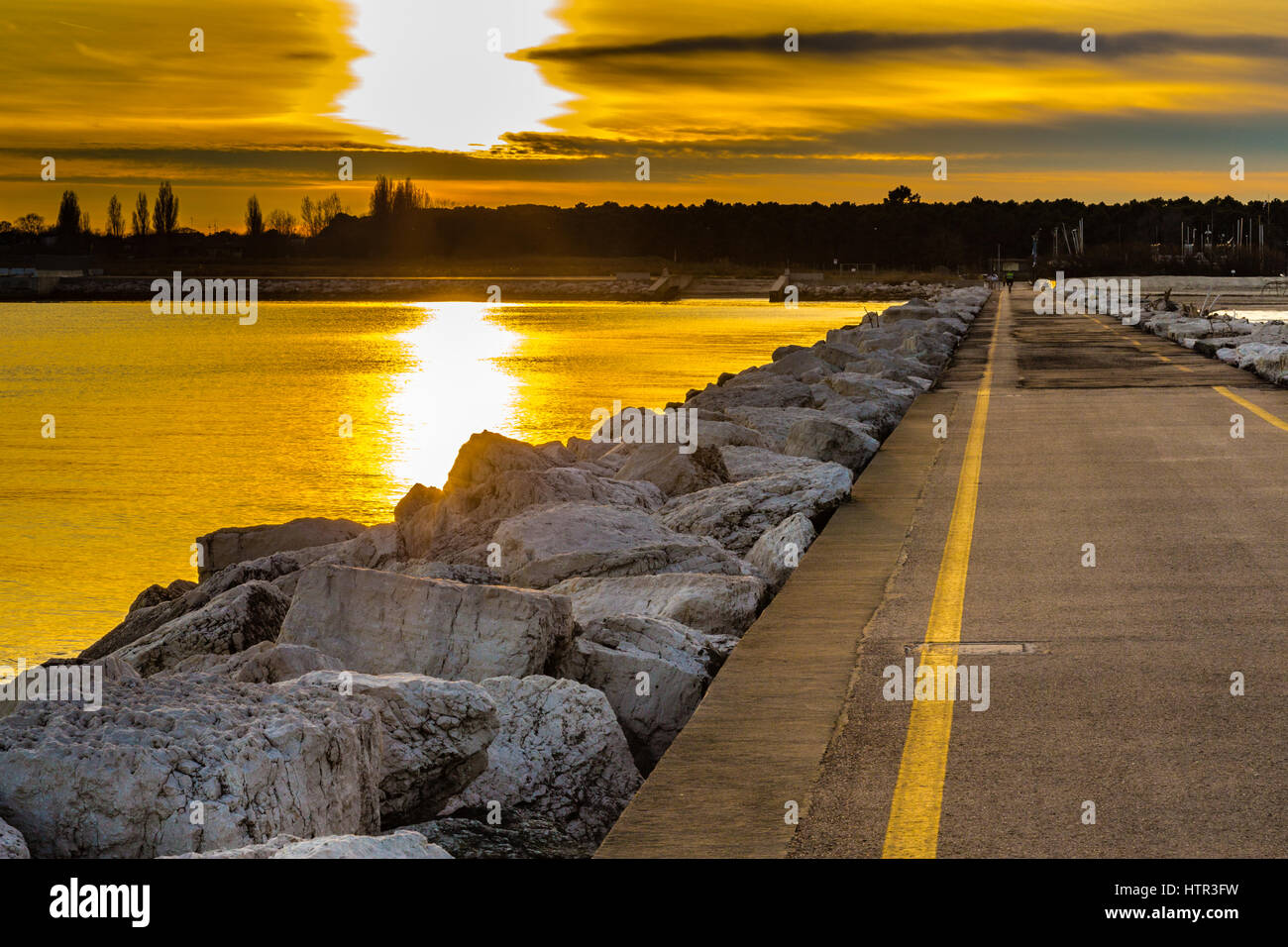 sunset on the pier paved road leading to the coast Stock Photo - Alamy