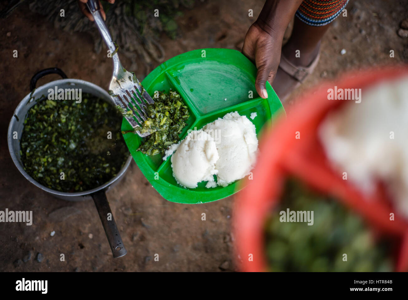 Serving nshima, traditional Zambian porridge, and vegetables for lunch ...