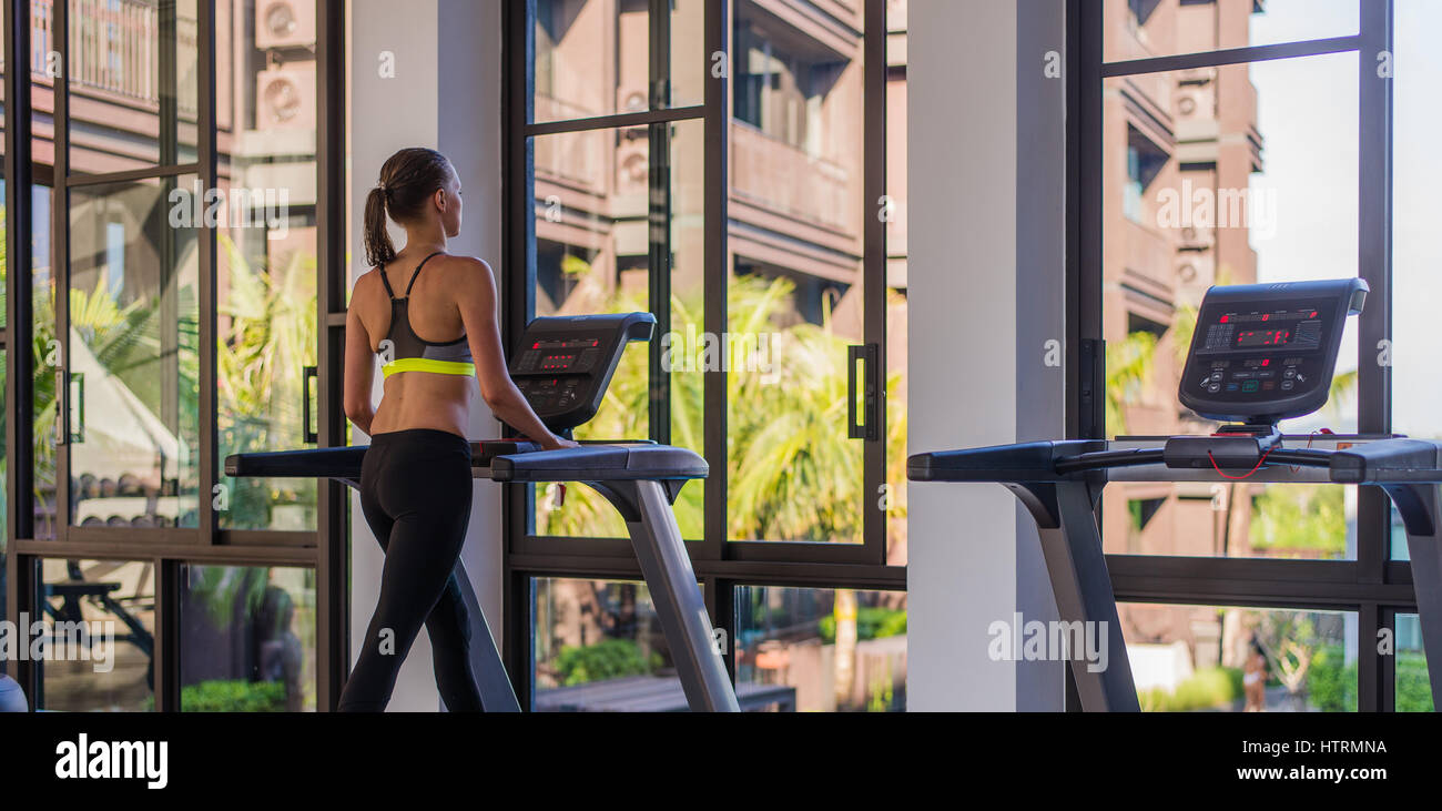 Horizontal shot of woman jogging on treadmill at health sport club at ...