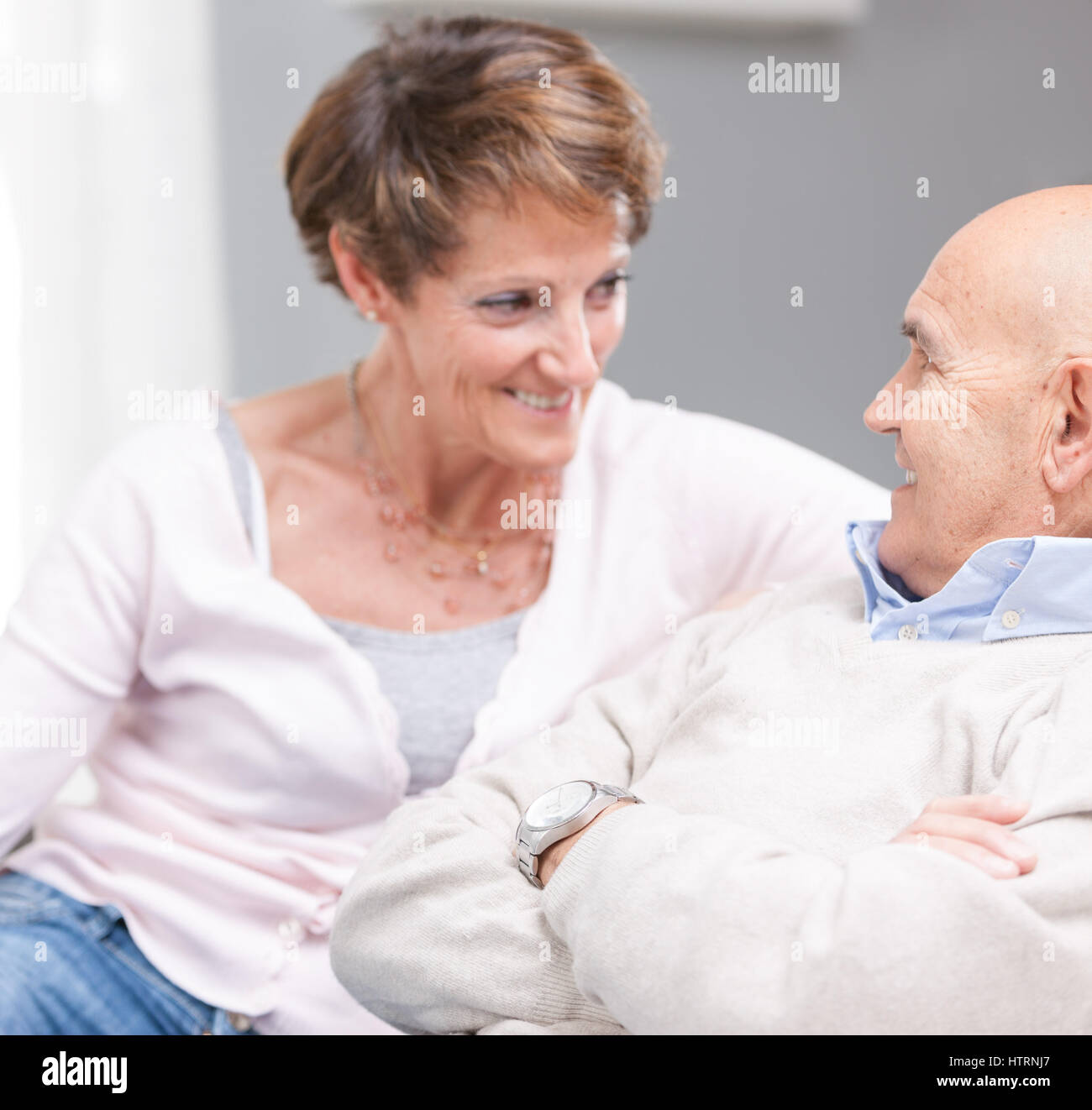 Loving happy middle-aged couple relaxing on a sofa looking into each ...