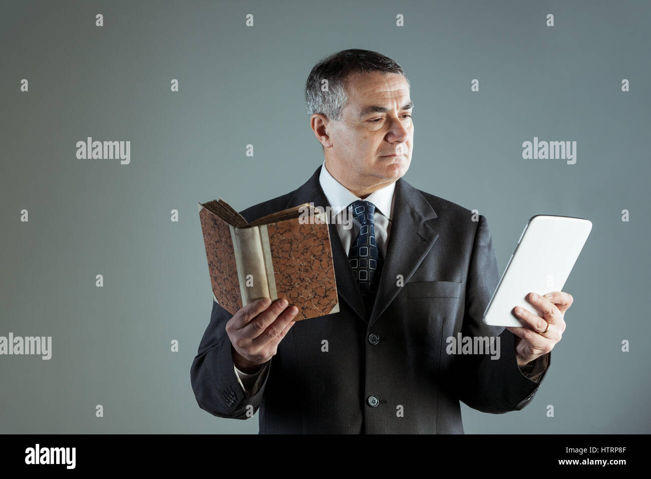 Portrait of an elegant senior man reading text from a modern tablet PC ...