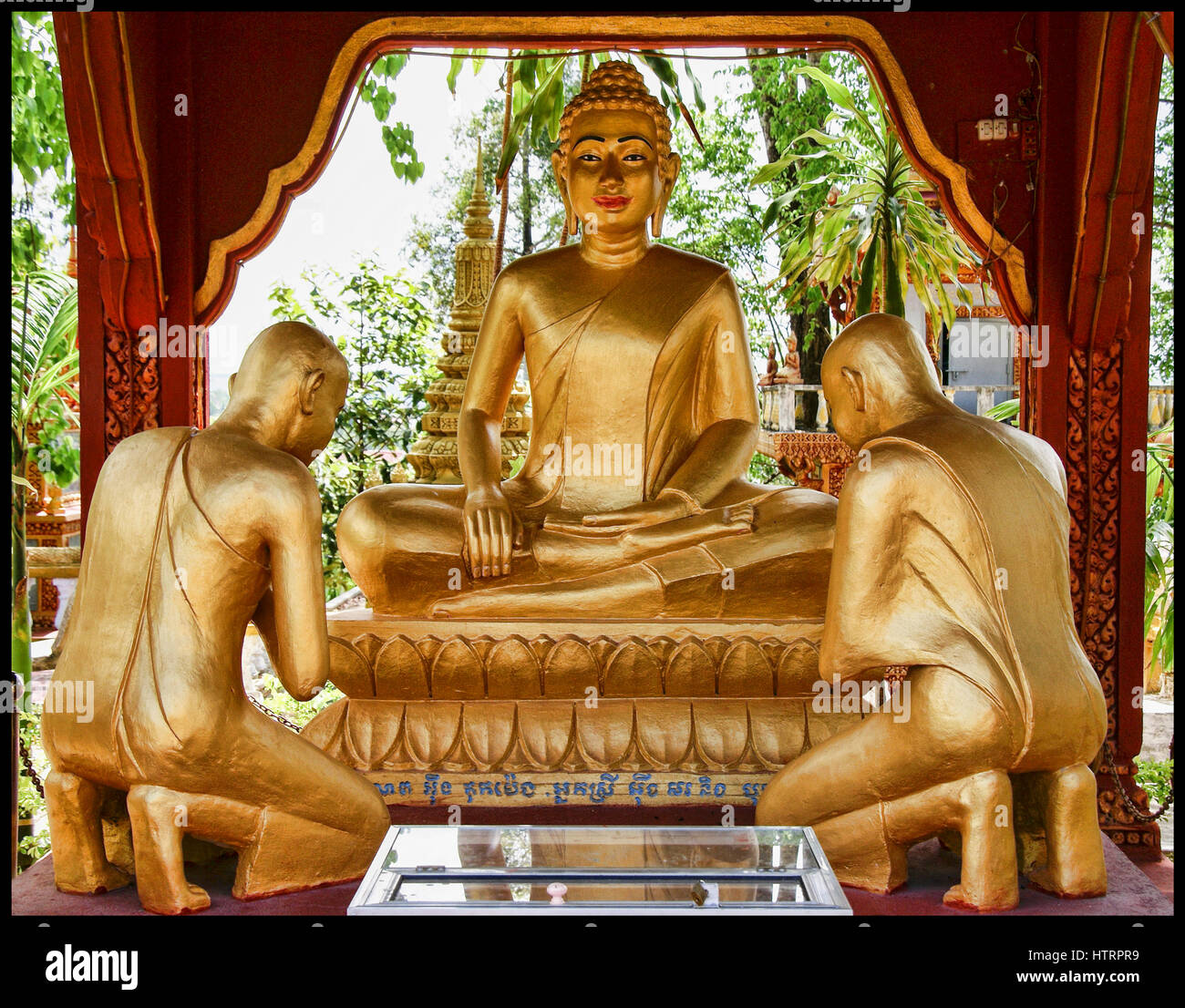Golden statues of Buddha and two monks at a temple in Cambodia ...