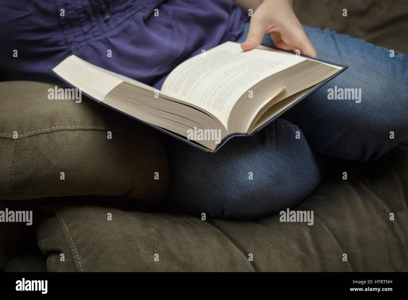 lazily reading a book on a sofa Stock Photo - Alamy