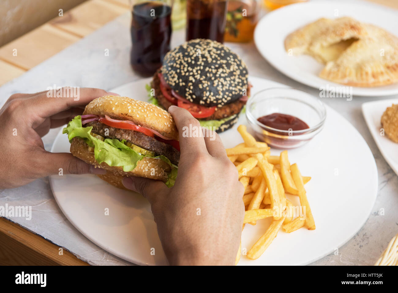 Man eating burgers at table, pov view Stock Photo - Alamy