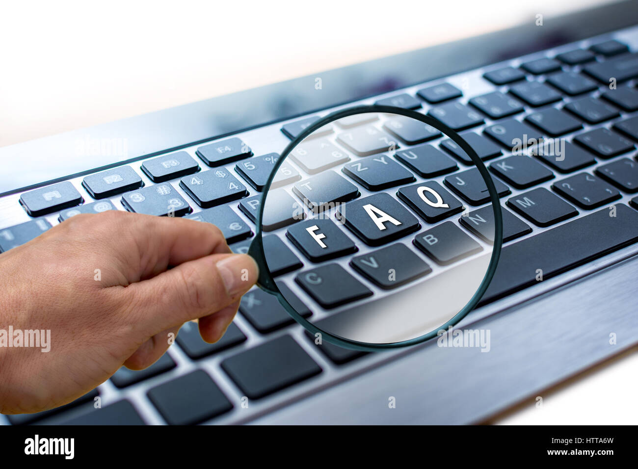 Mans hand with magnifier. Keyboard of computer or laptop with sign faq ...