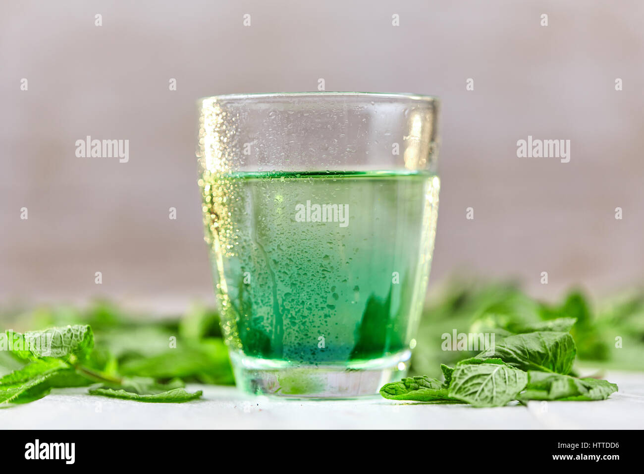 Green mint chlorophyll drink in glass with water drops on white table ...