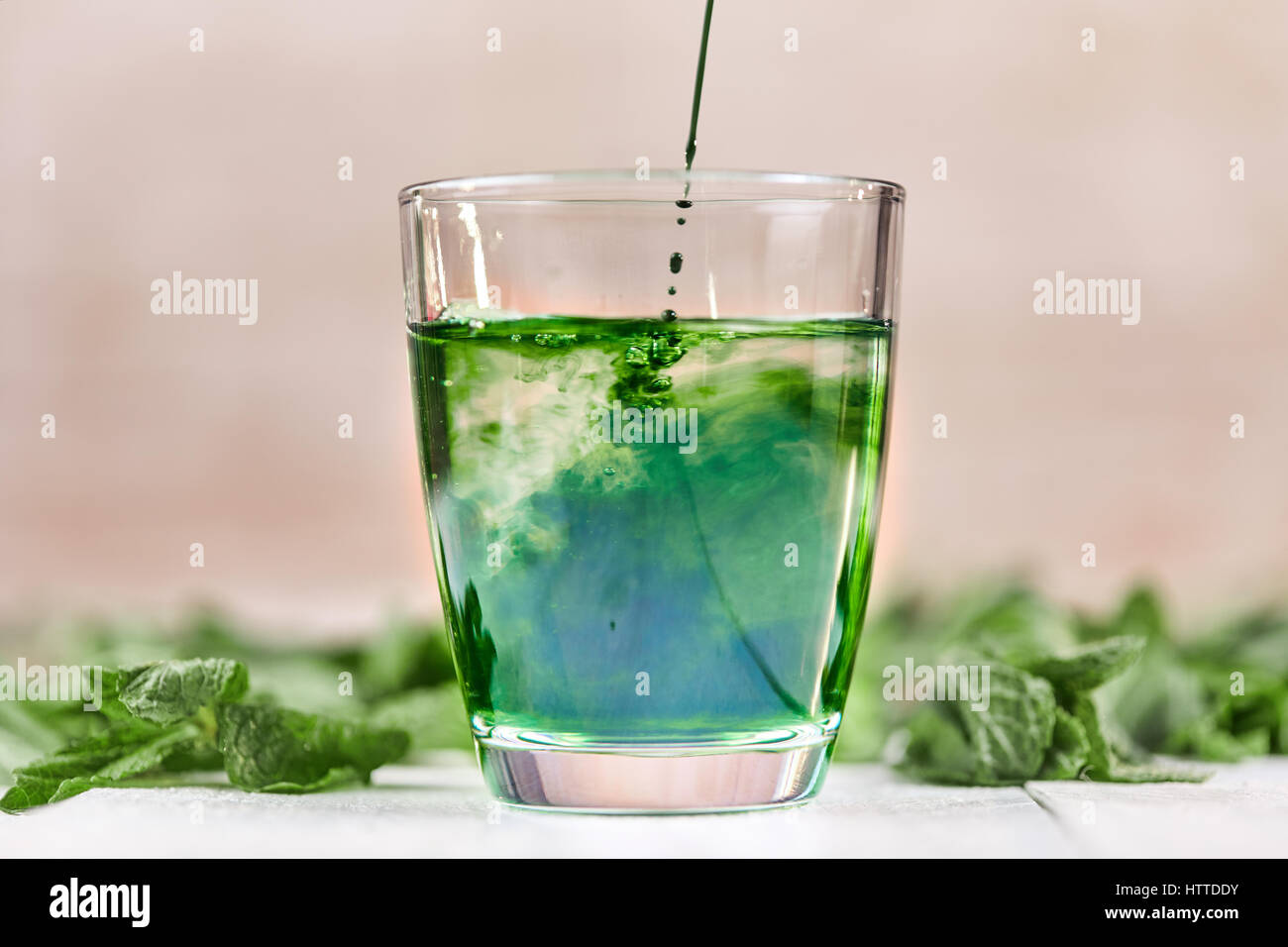 Green chlorophyll drink in glass with water on white table with green ...