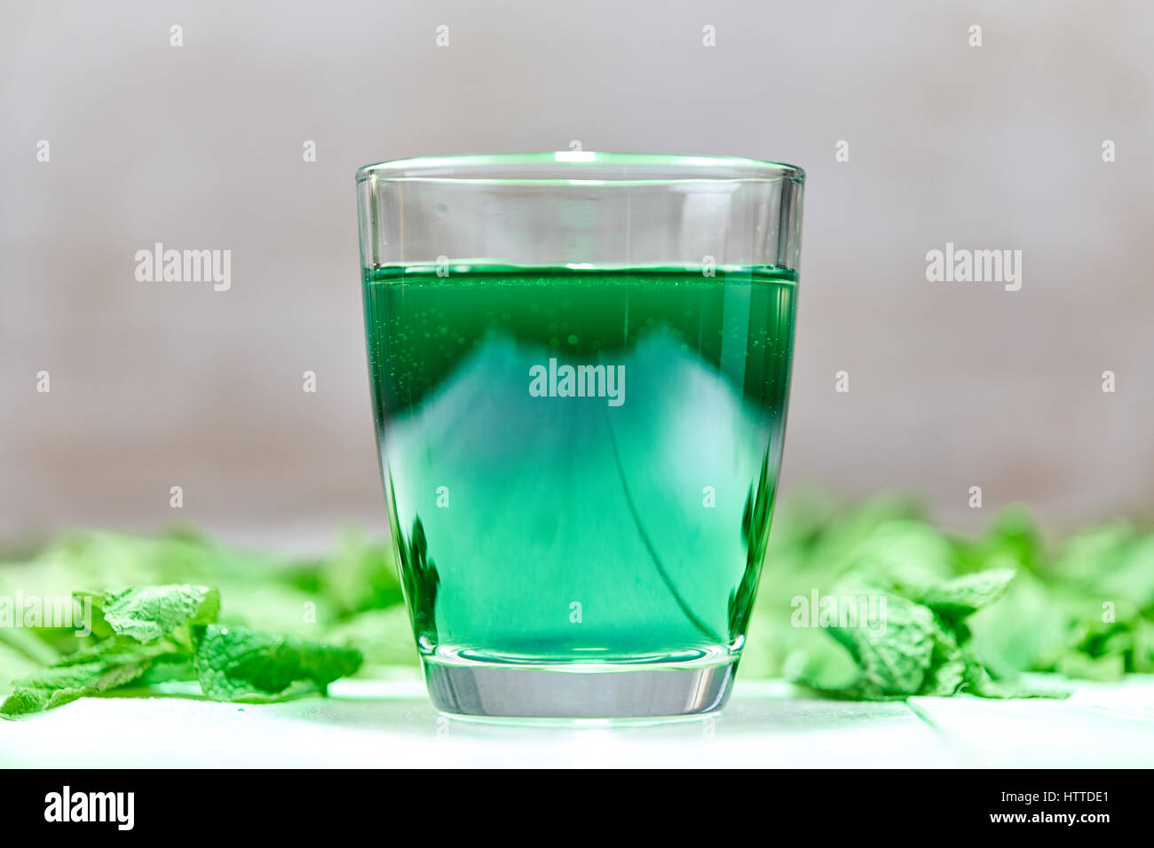Green chlorophyll drink in glass with water on white table with green ...