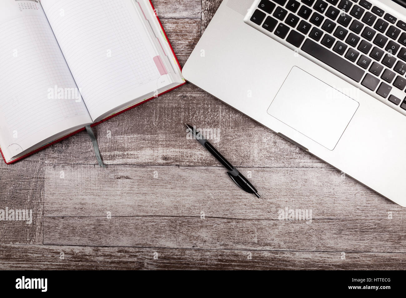 Open writing notebook next to a laptop from above view on a wooden ...