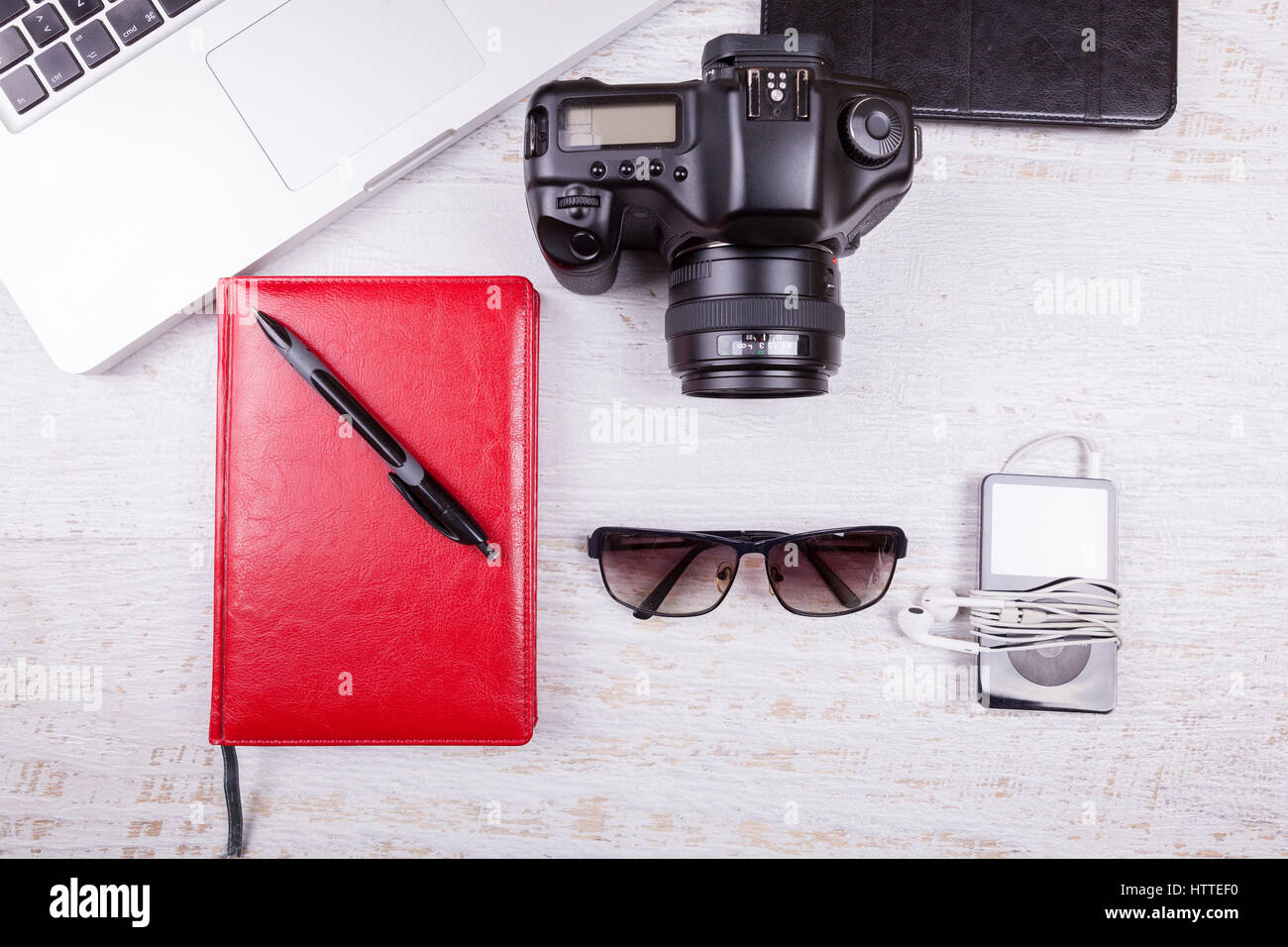 Laptop, writing notebook, camera and musical player on wooden ...