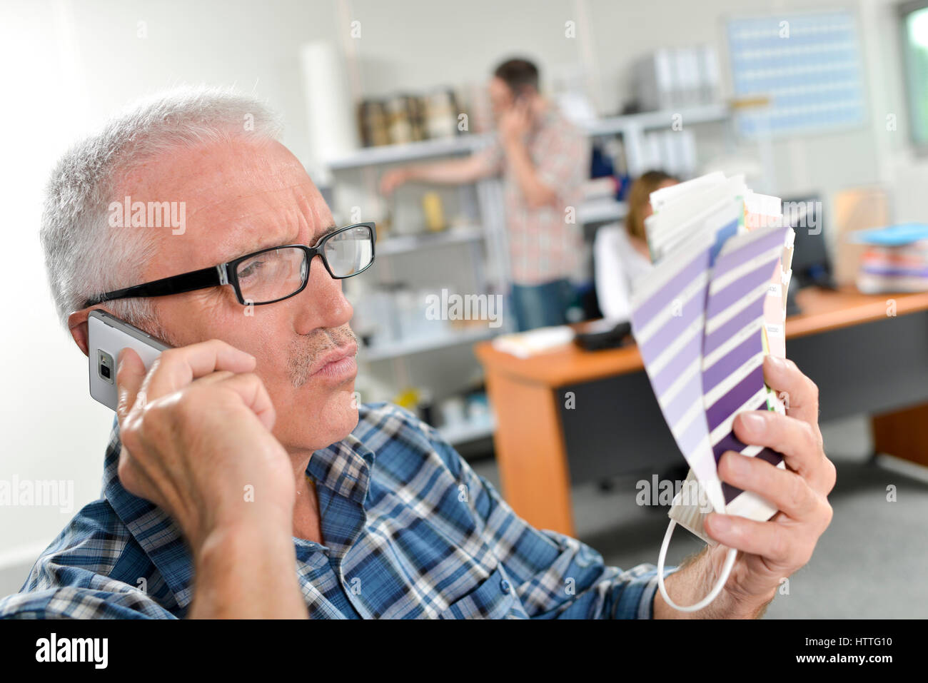 Man on telephone holding colour charts, looking skeptical Stock Photo ...