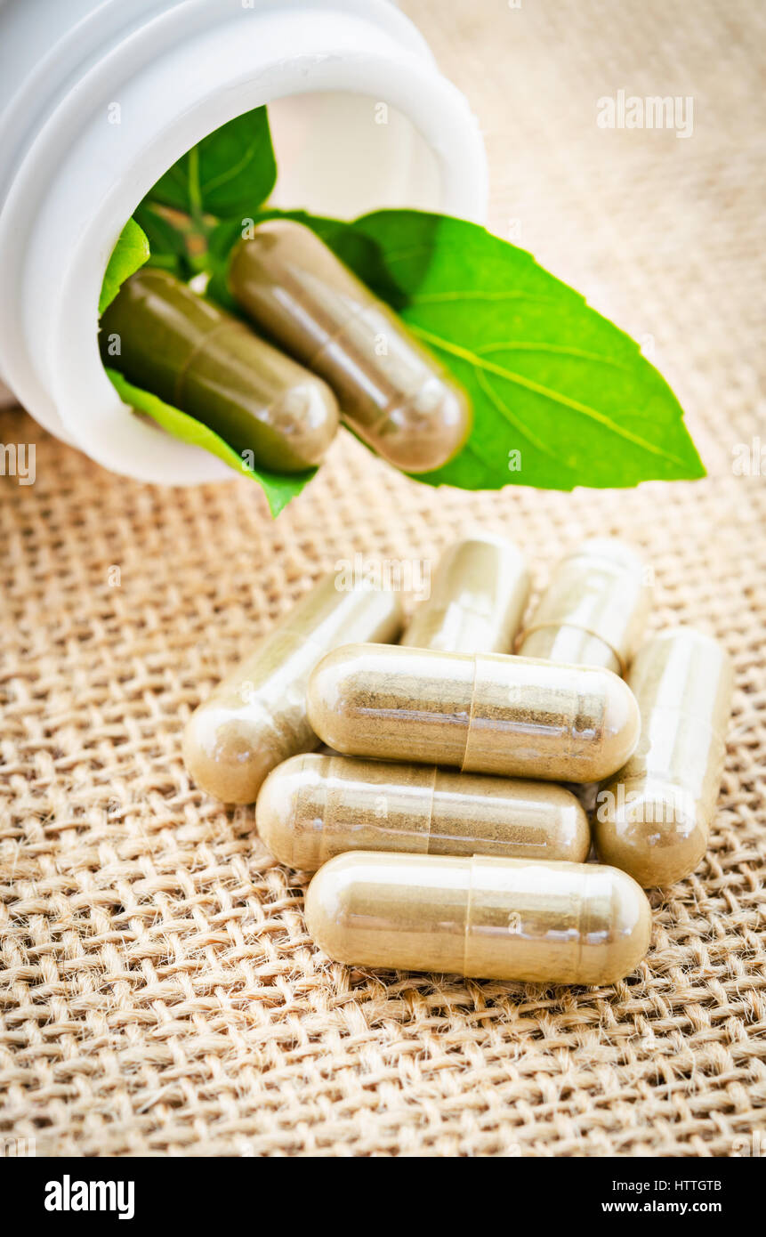 Herb capsule spilling out of a bottle with green leaf on sack background Stock Photo - Alamy