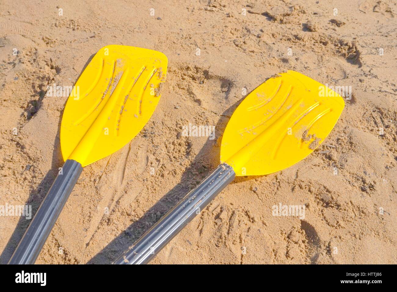 Yellow oars on sandy beach with black handles for rowing Stock Photo ...