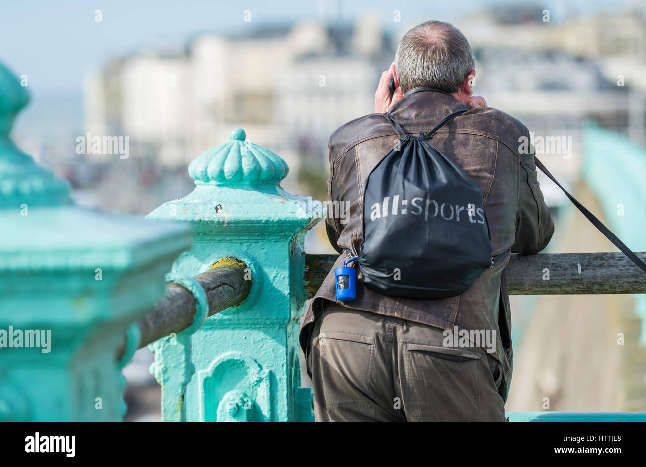 Man standing over railings while speaking on his phone Stock Photo - Alamy