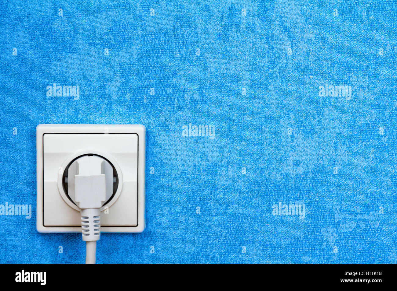 Electrical plug connected into the socket on blue wall Stock Photo - Alamy