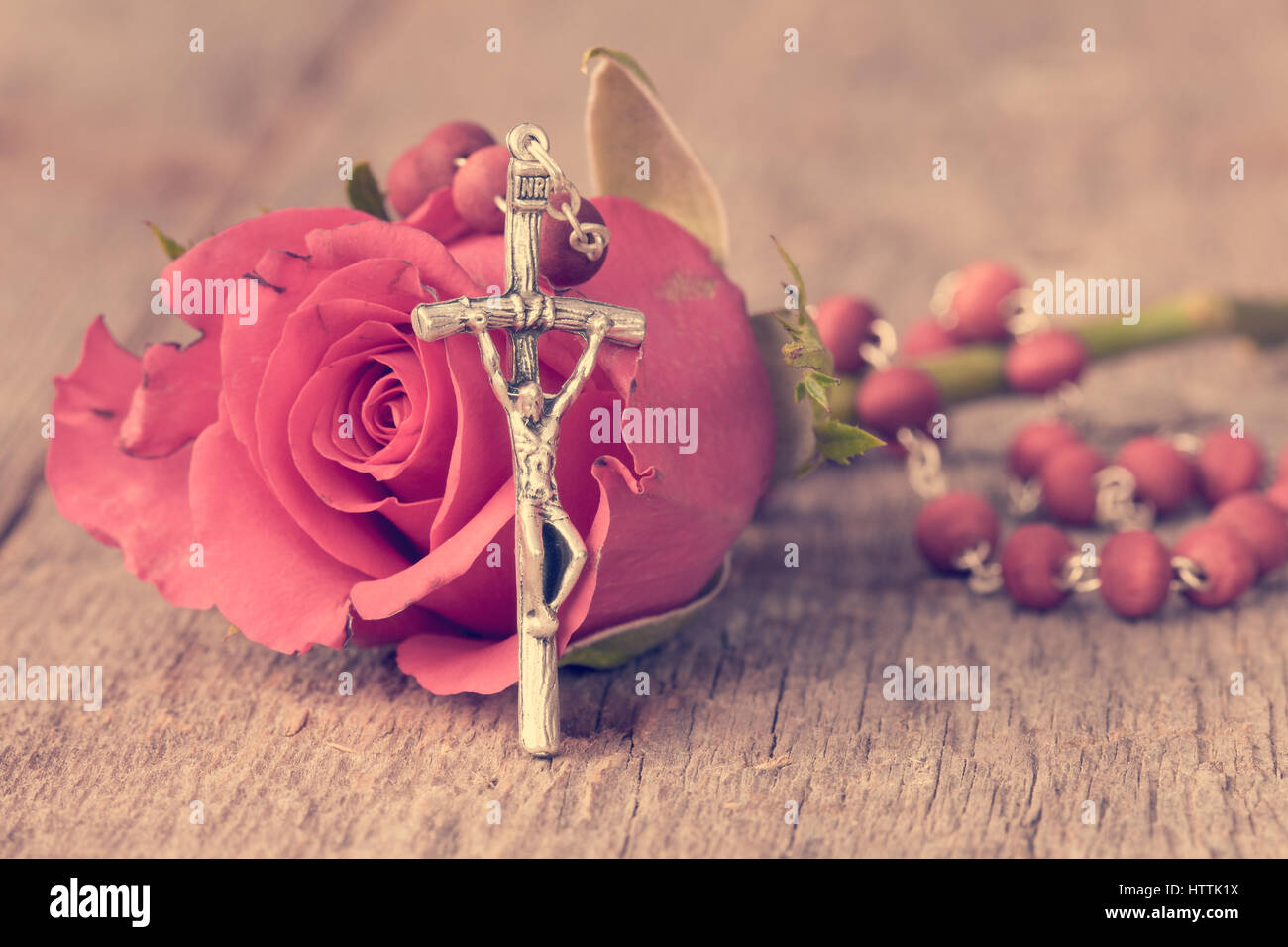 Silver crucifix and single rose on wooden background.Pastel colors ...