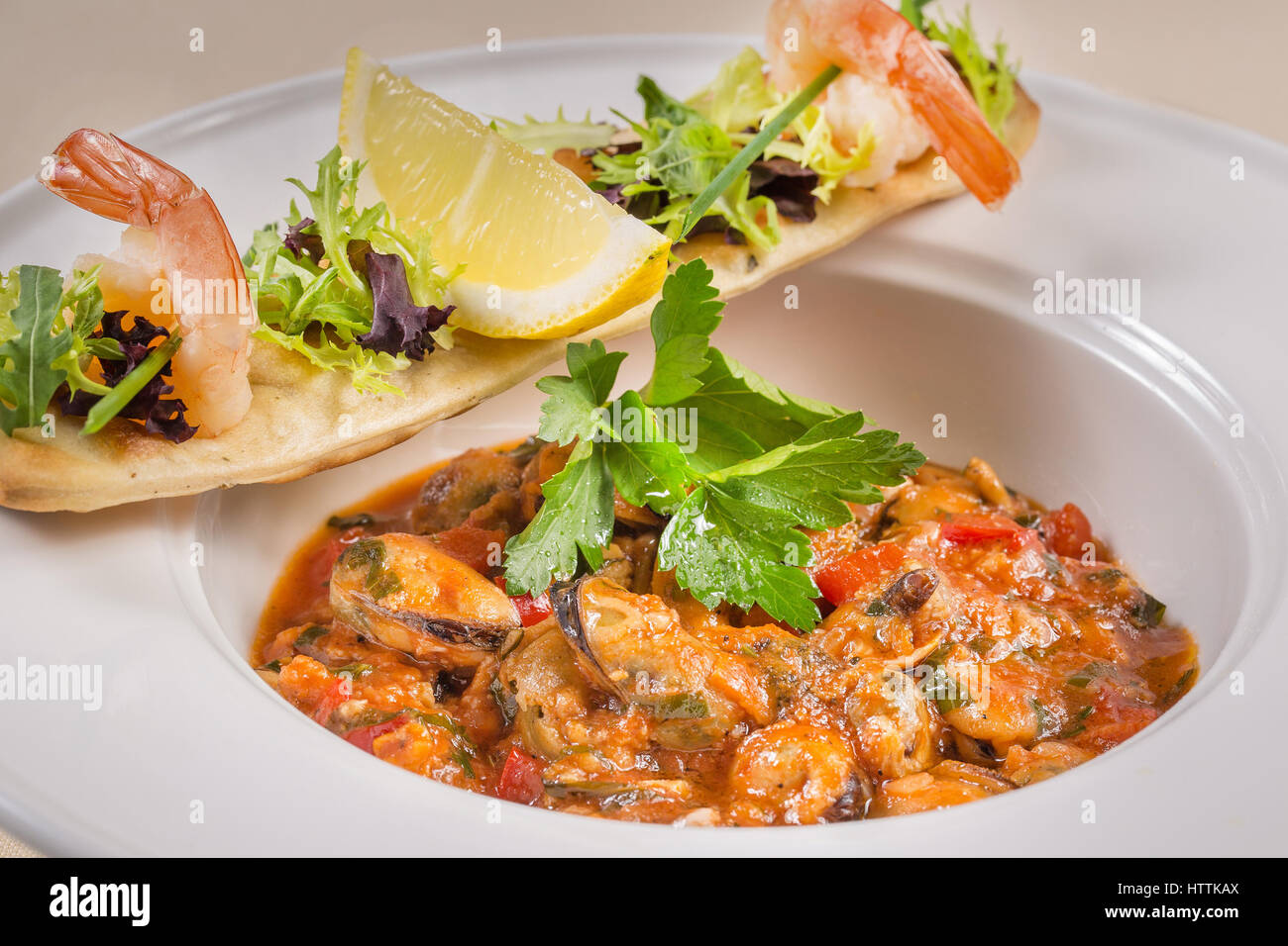 Mussels cooking with lemon and herbs in clay pot over dark wood ...