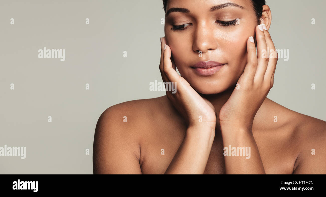 Closeup of a beautiful young woman with perfect healthy skin on grey ...