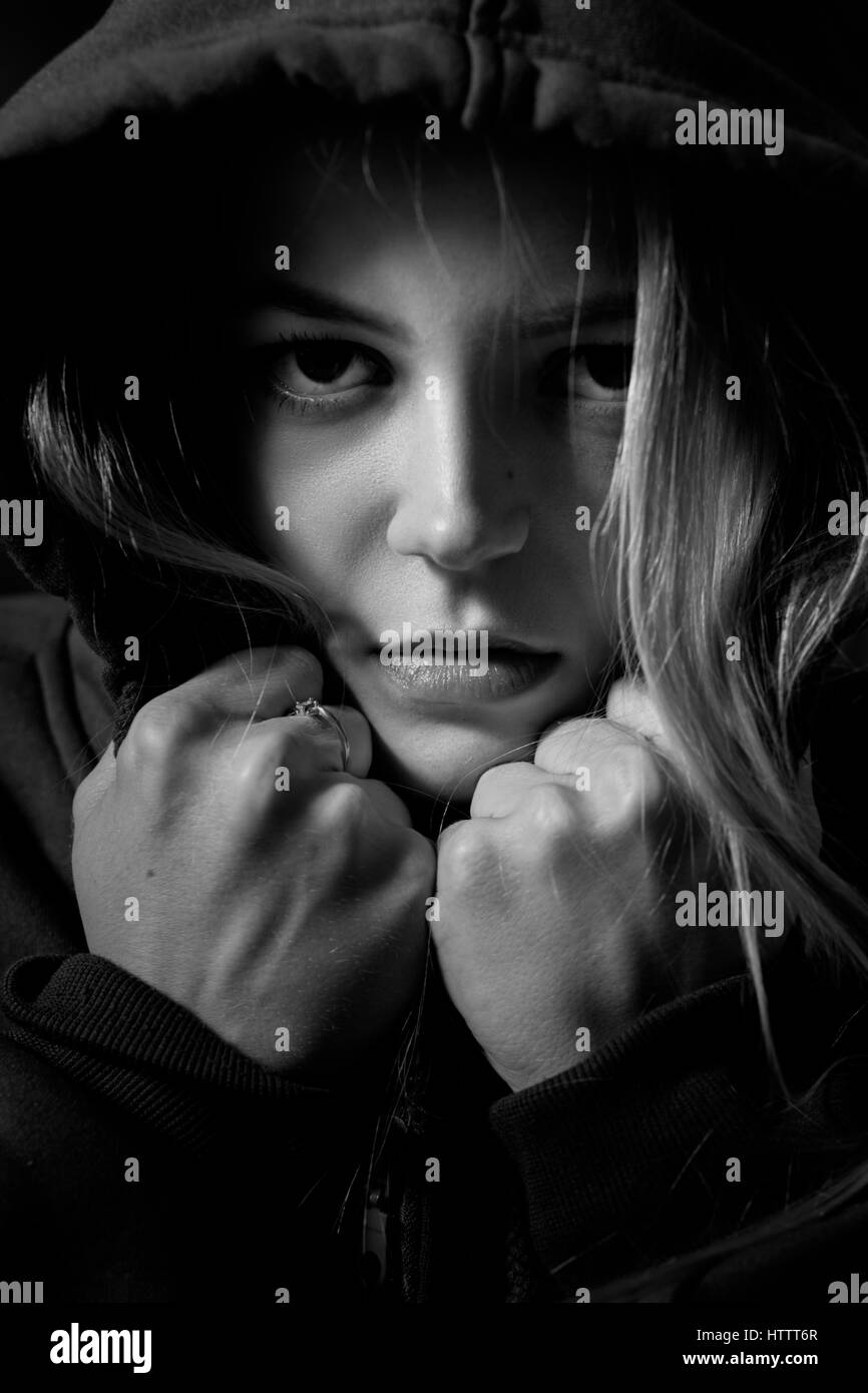 scared girl in hood looking at camera on black background monochrome ...