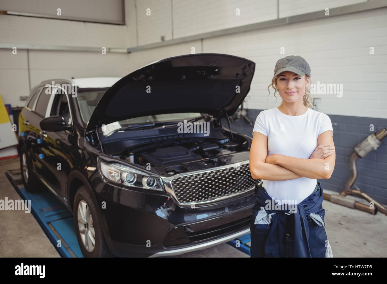 Female mechanic standing with arms crossed in front of car Stock Photo ...