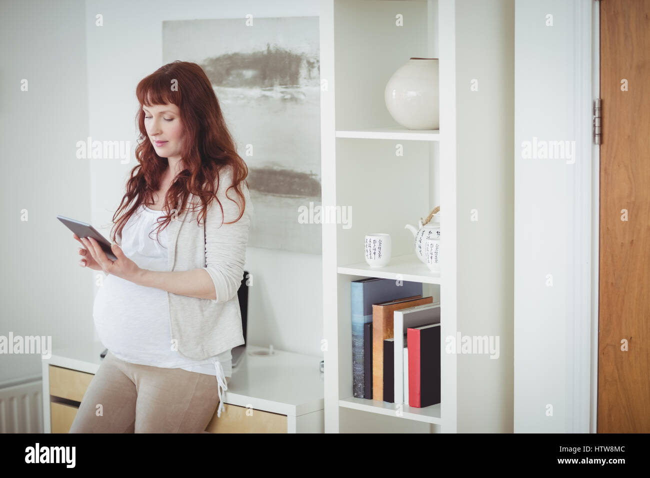 Pregnant woman using digital tablet in study room Stock Photo - Alamy