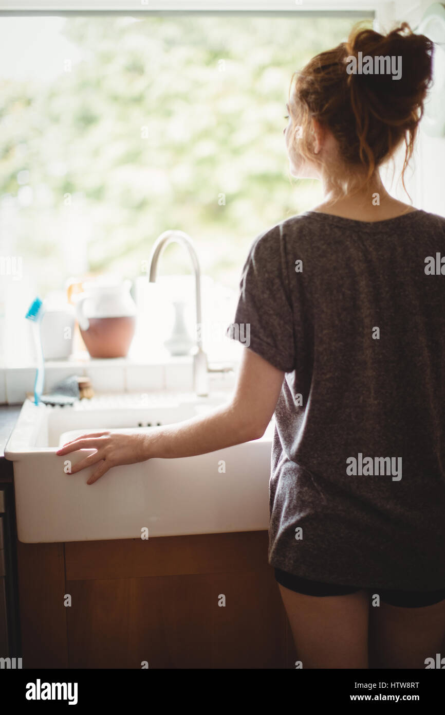 Woman looking through window at home Stock Photo - Alamy