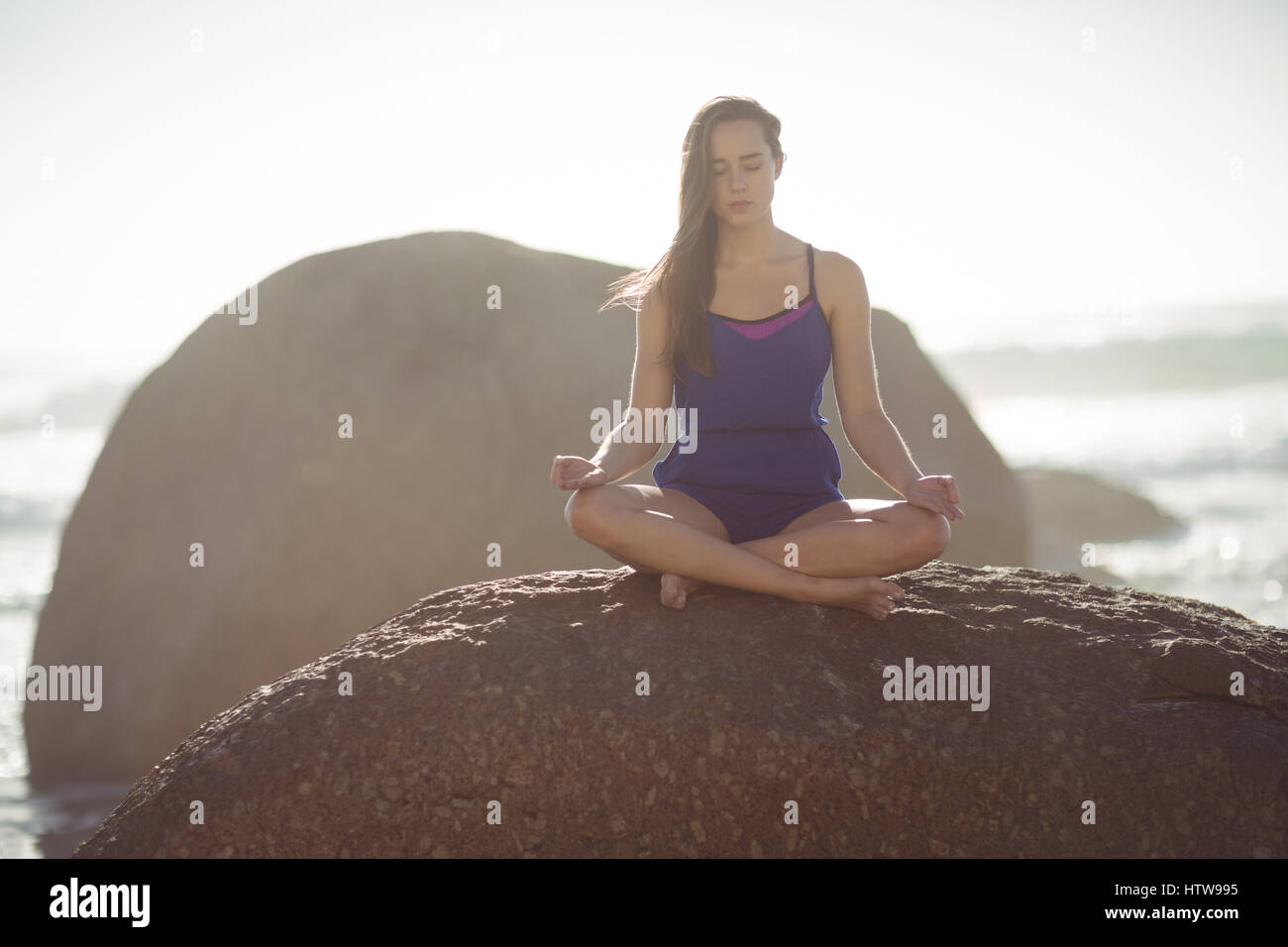Beautiful woman performing yoga on rock Stock Photo - Alamy