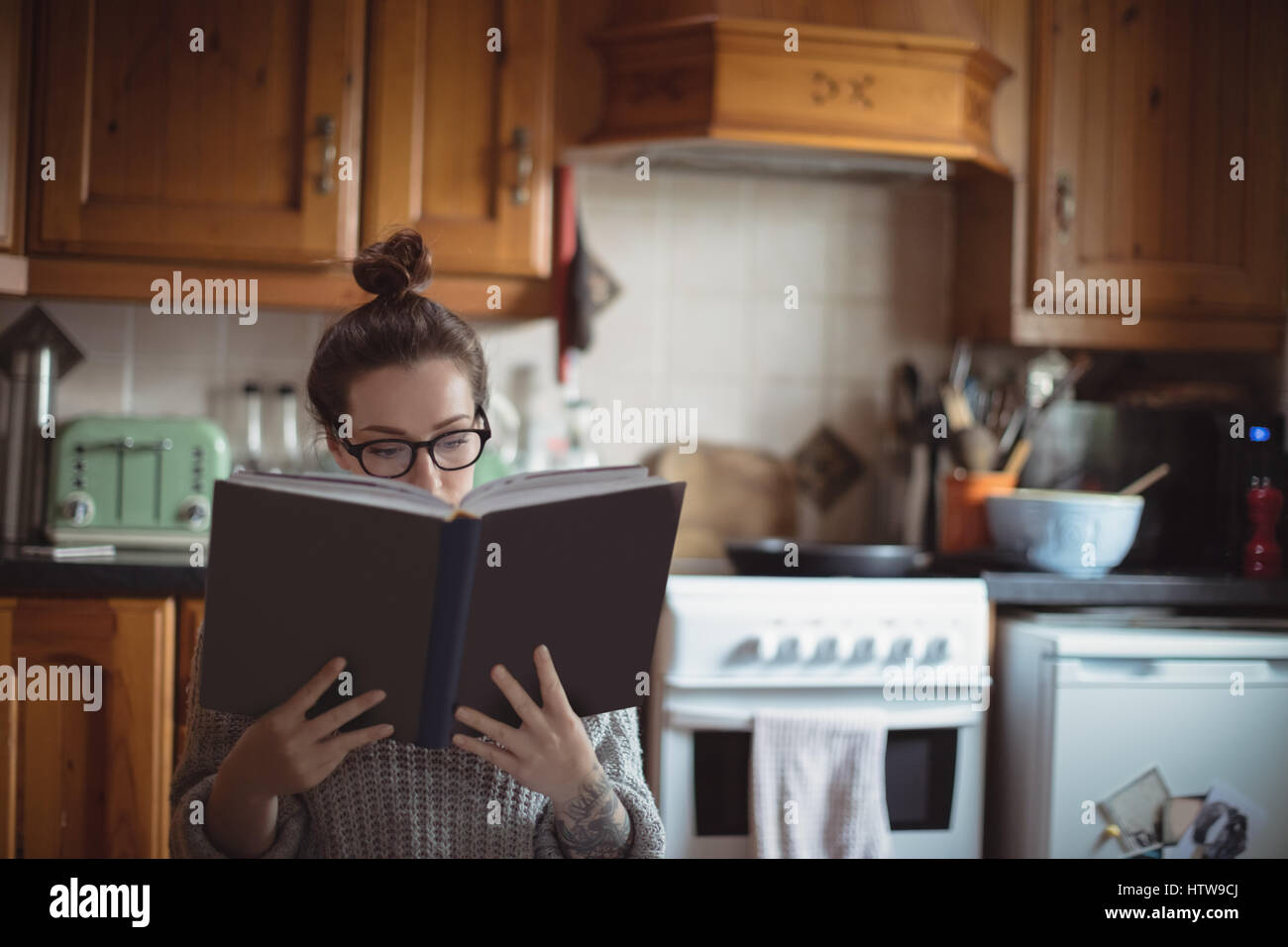 Woman reading book in kitchen Stock Photo - Alamy