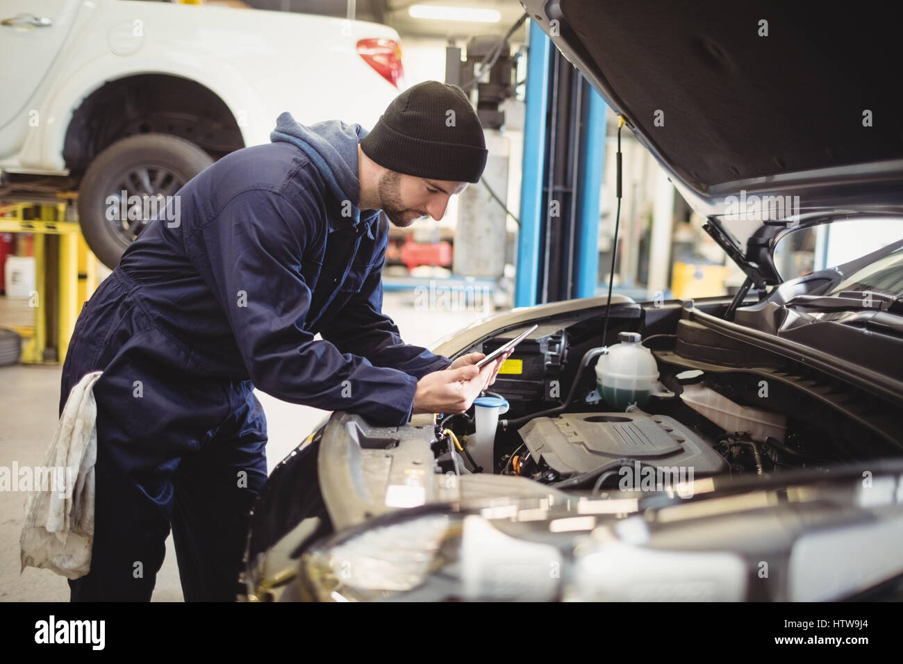 Mechanic using digital tablet on car Stock Photo - Alamy