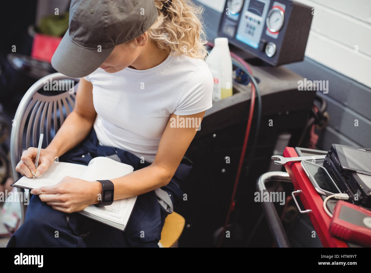 Female mechanic writing on diary Stock Photo - Alamy