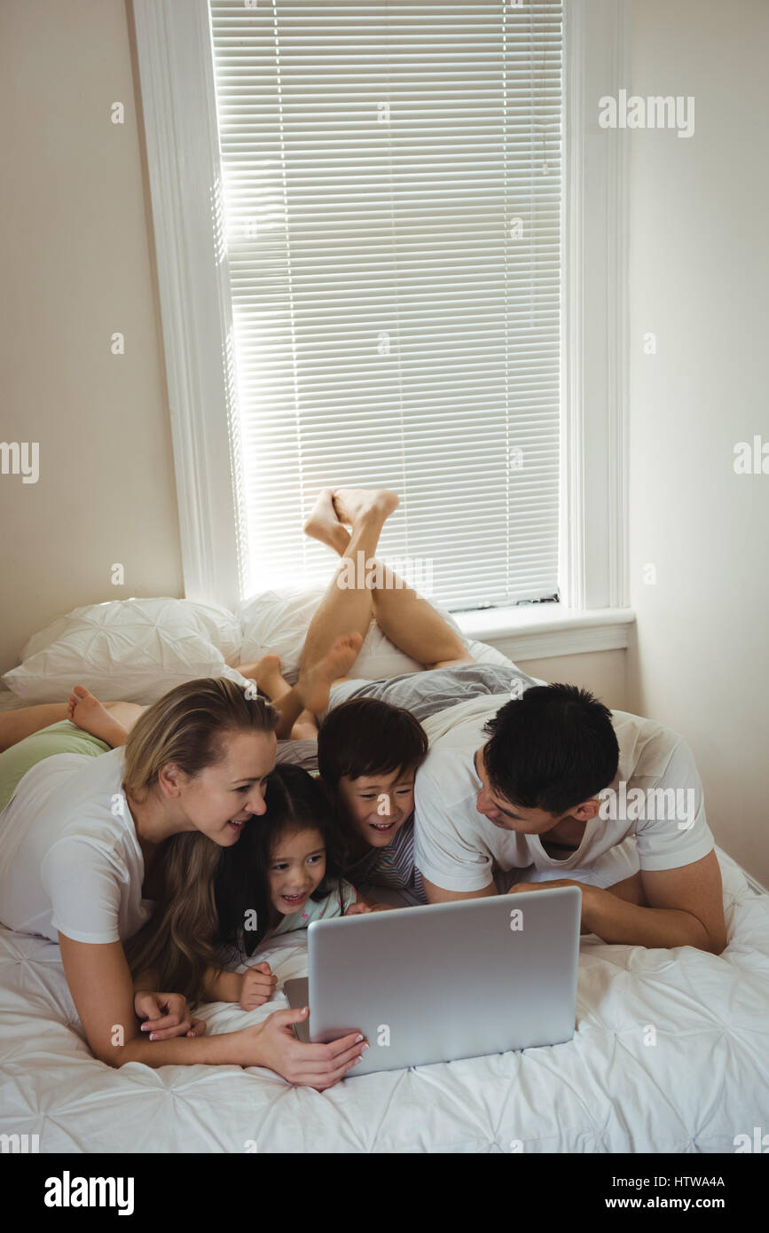 Happy family using laptop in bedroom Stock Photo - Alamy