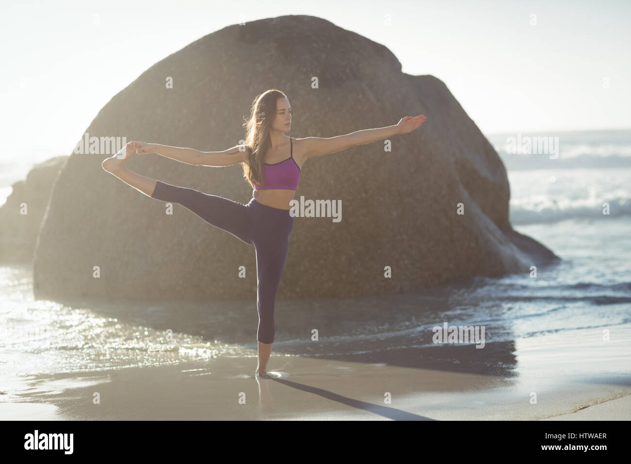 Beautiful woman performing stretching exercise on beach Stock Photo - Alamy